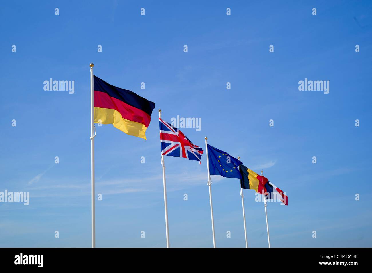 Five flags representing Germany, UK, EU, France, and Belgium waving against a clear blue sky ...
