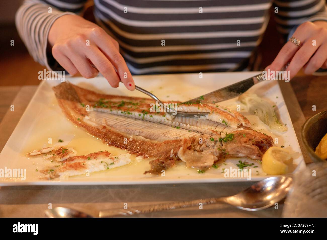 Woman with funny nail design enjoying a meal of grilled fish with herbs ...