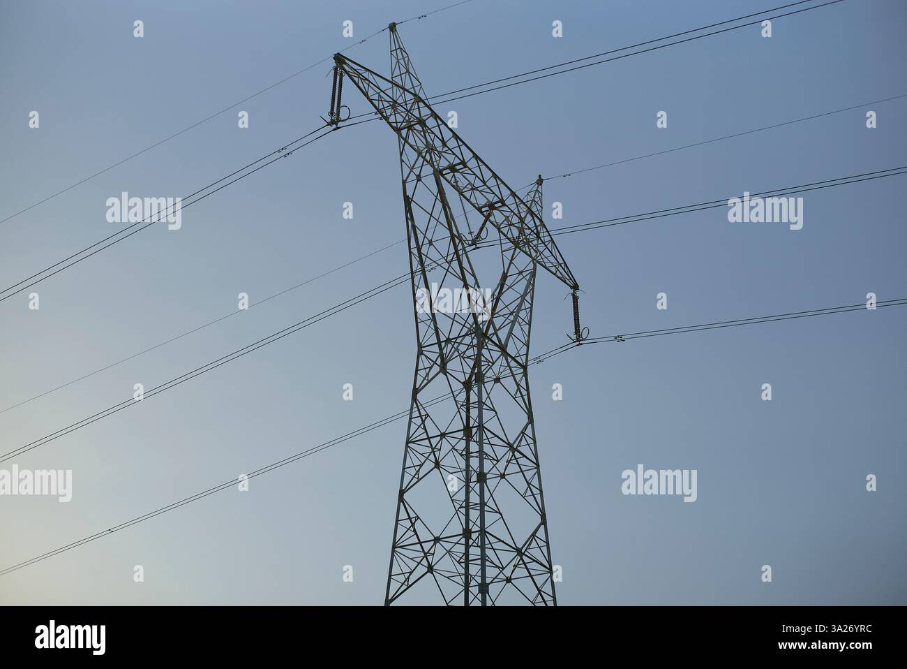 Tall metal electricity pylon with intricate wires against a clear blue ...