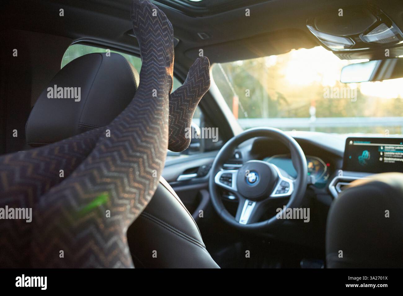 Woman relaxes in car with legs in tights on dashboard, interior view ...