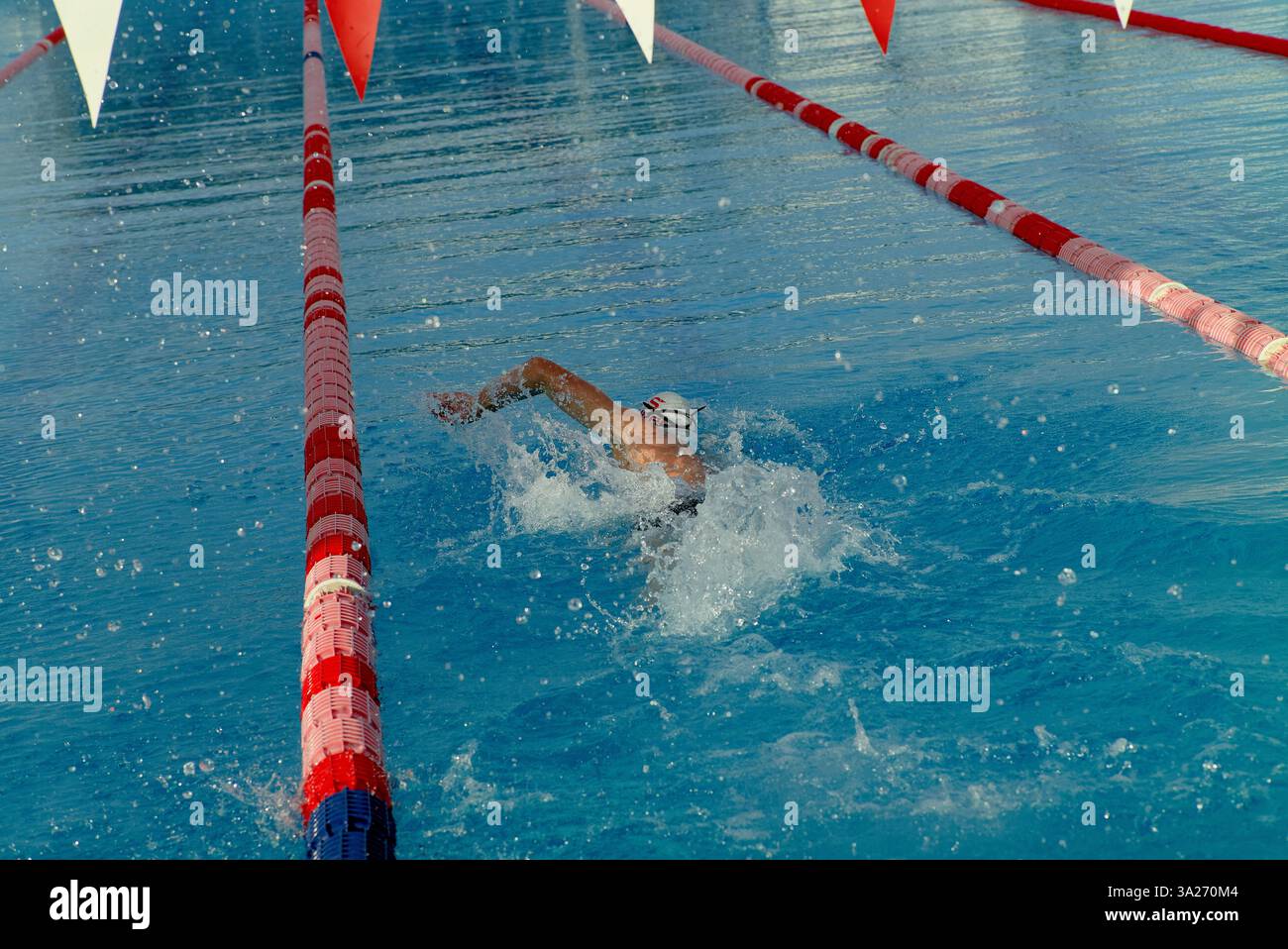 Triathlon swimmer actively competing in an outdoor pool lane with clear ...