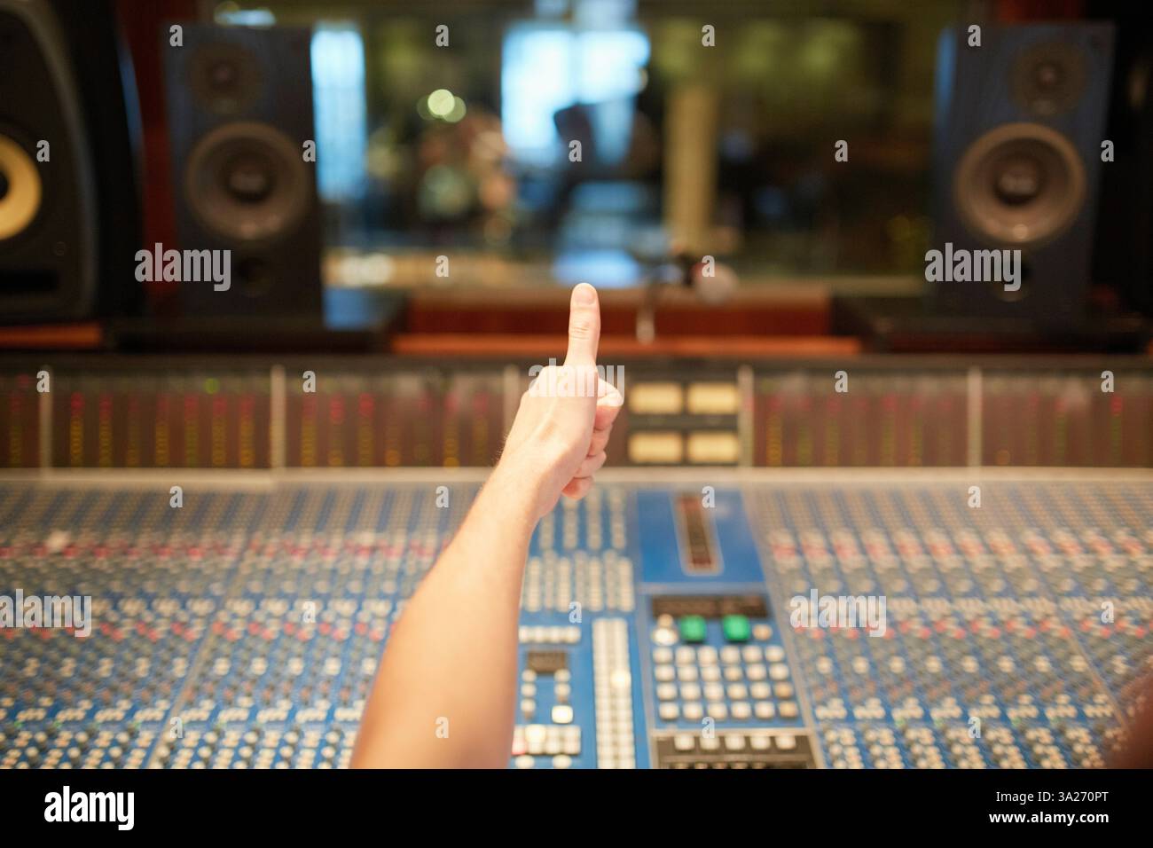 Hand giving thumbs up behind a large studio sound mixing console with ...