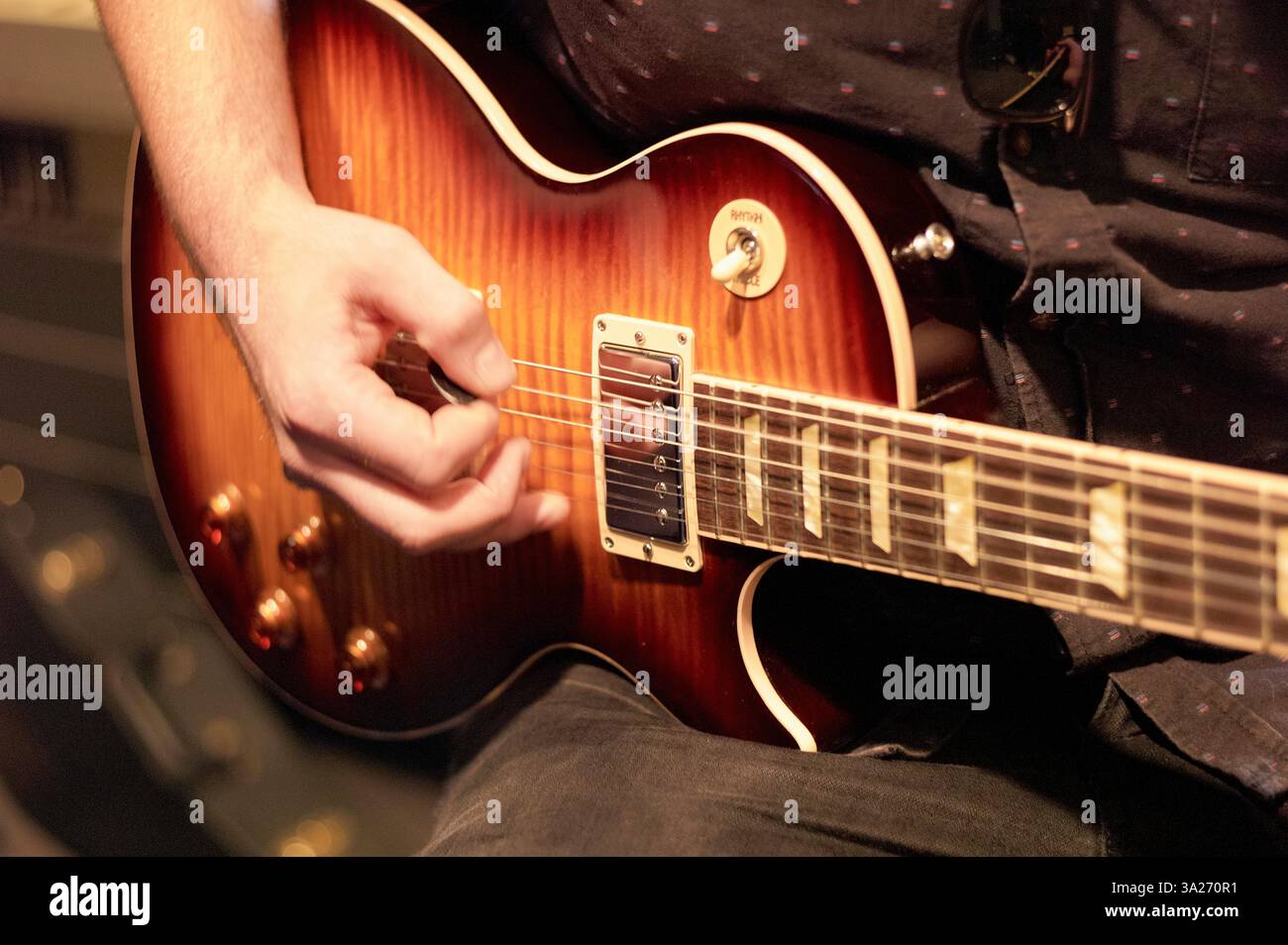 Close-up of a person's hand playing a sunburst electric guitar during a ...