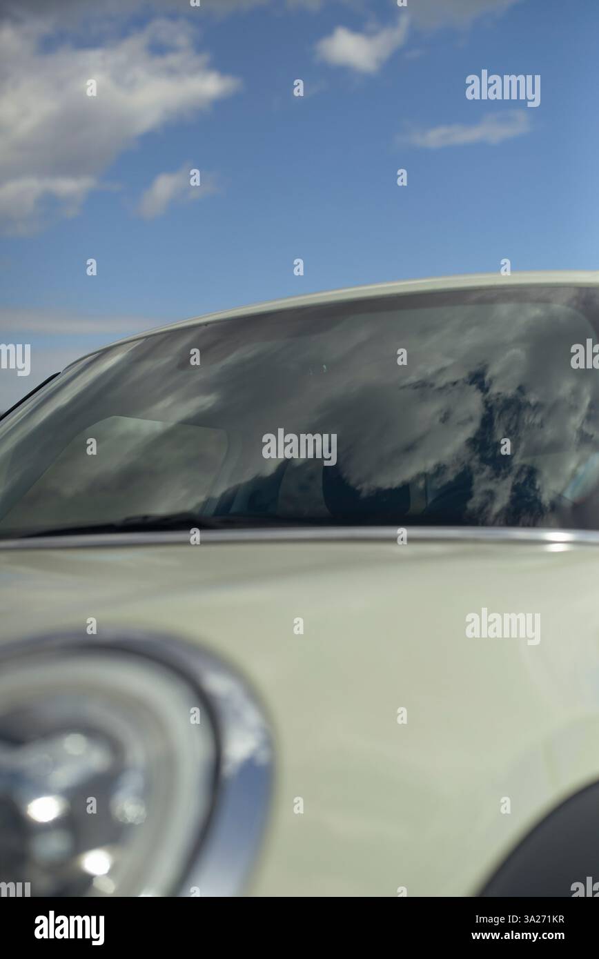 Close-up view of a sleek car with a reflection of clouds and blue sky ...