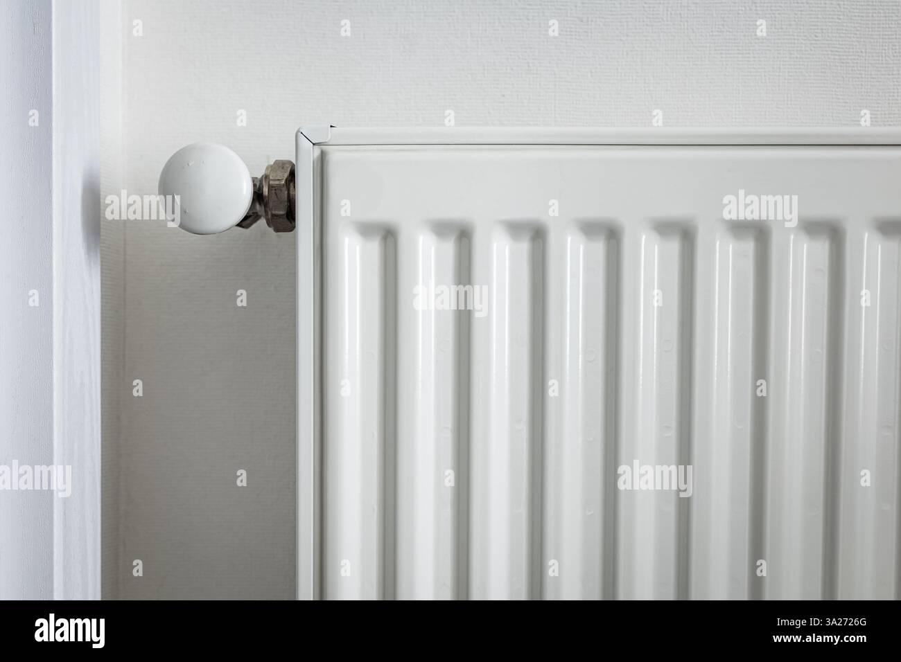 Close-up of a white metal radiator with a temperature control valve ...