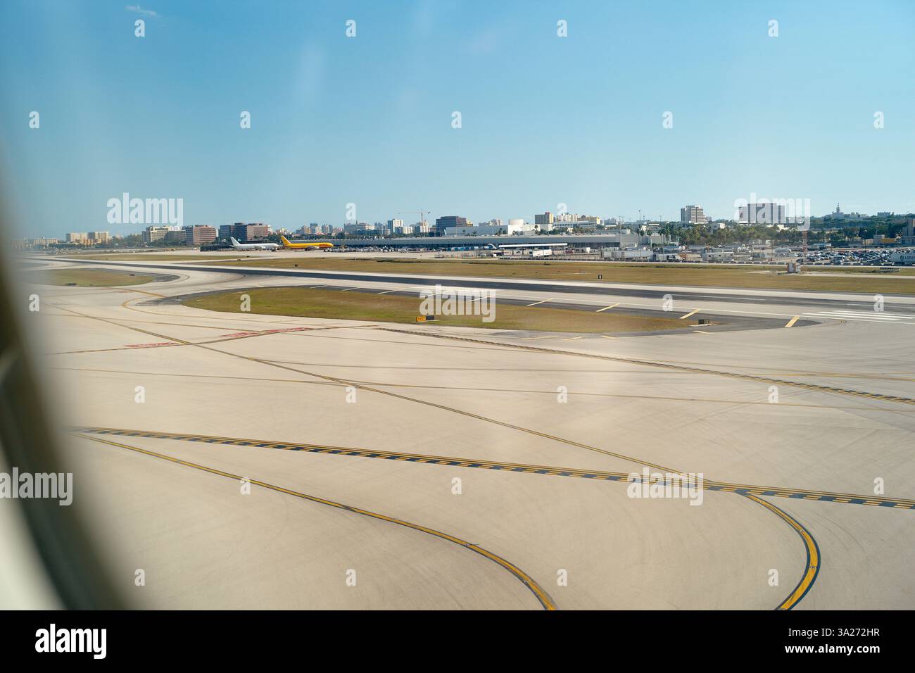 View from airplane window of airplane taxiing on runway at a busy urban ...