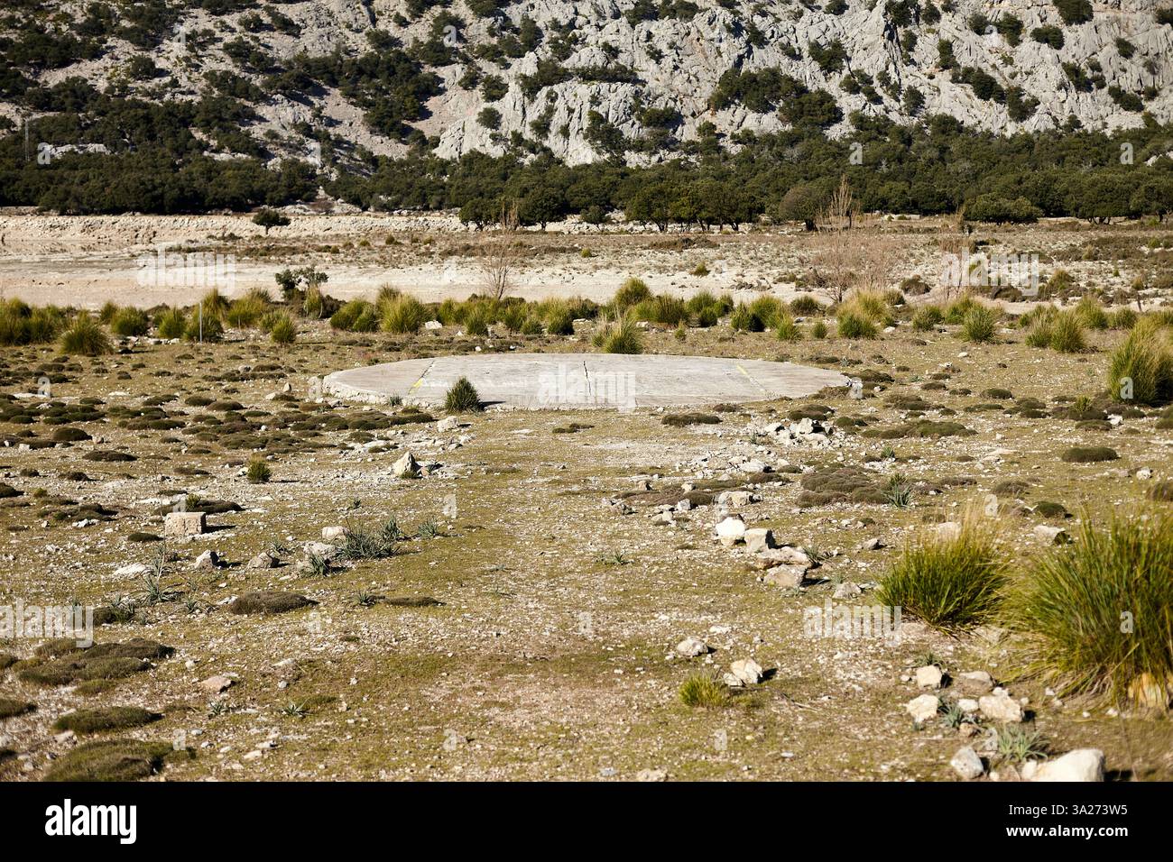 Circular concrete slab surrounded by rocky terrain and sparse ...