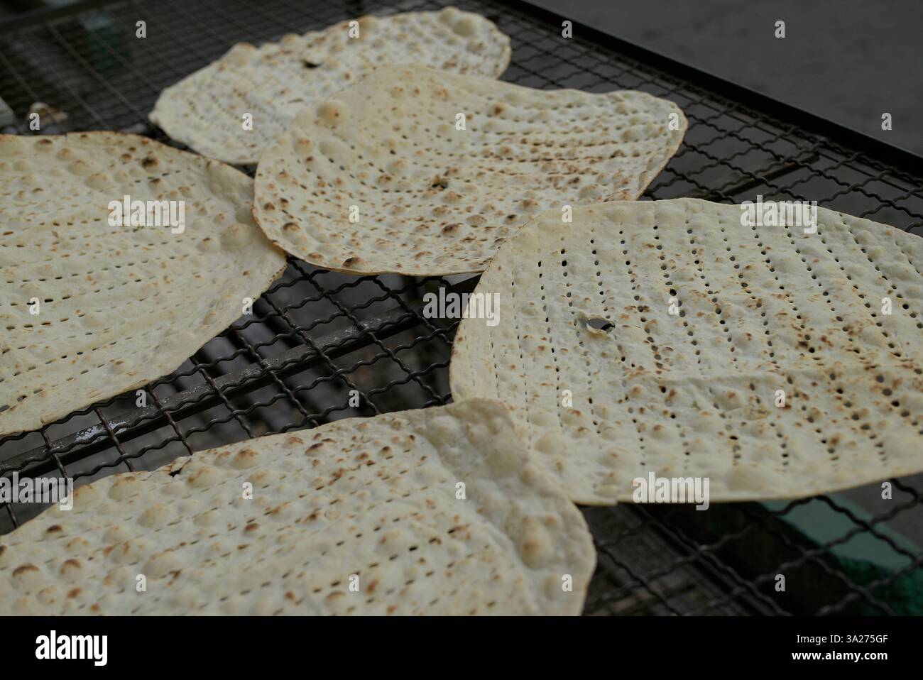 Thin flatbreads with perforated patterns baking on a metal rack ...