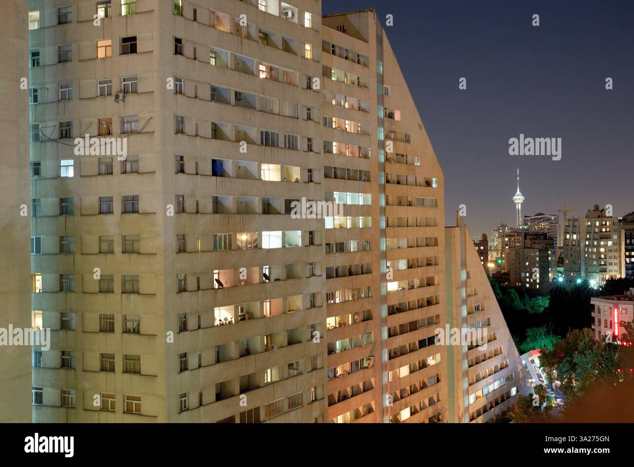 Illuminated high-rise apartment buildings at night with city skyline in ...