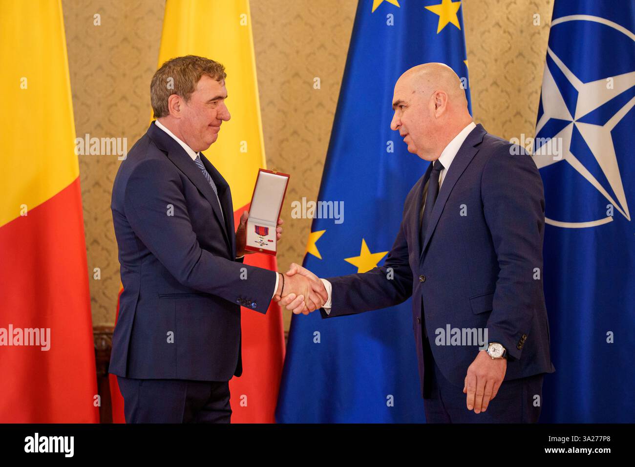 Romania's interim President Ilie Bolojan, right, shakes hands with ...
