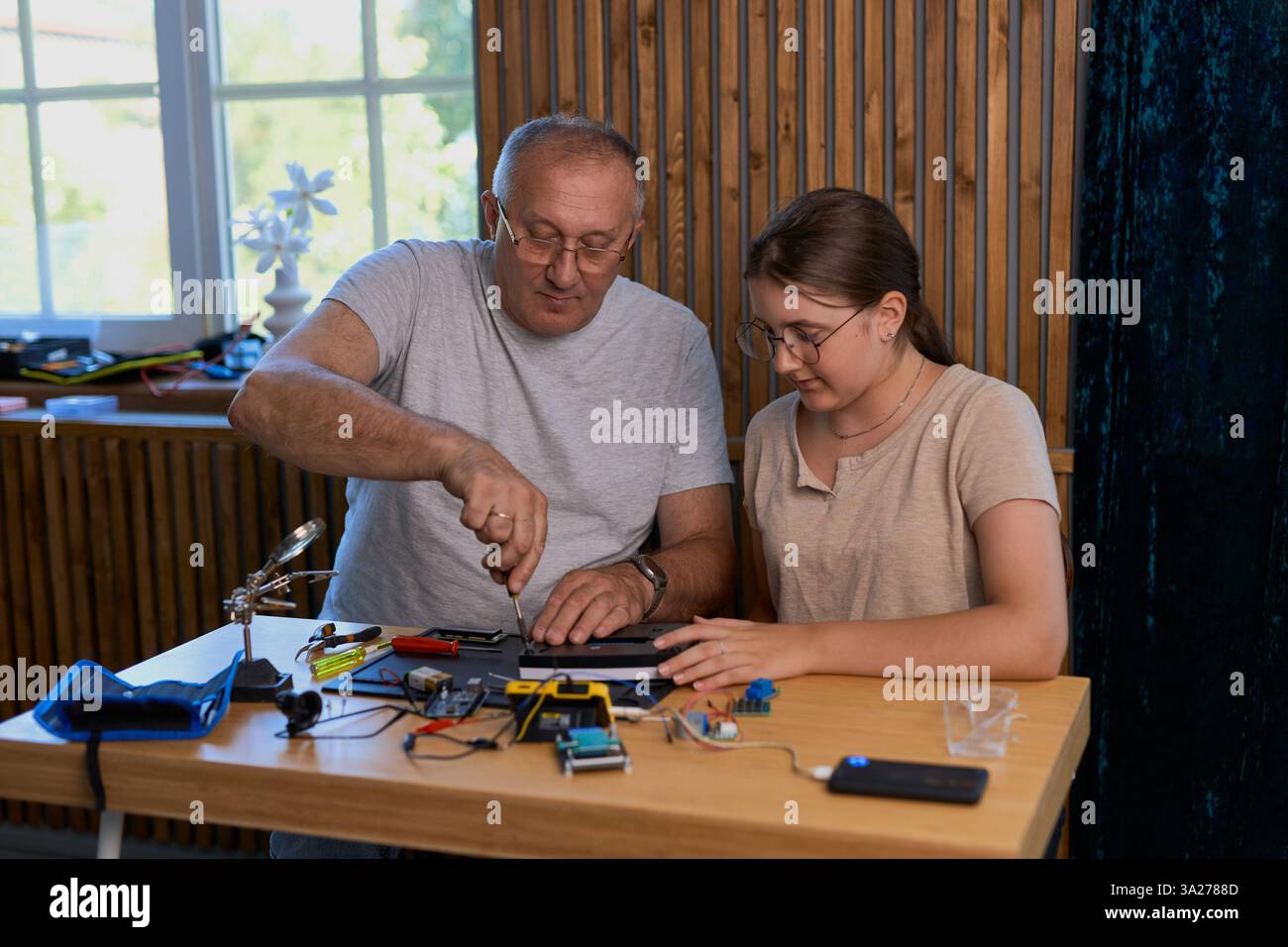 Grandfather teaches his granddaughter how to repair electronic devices ...