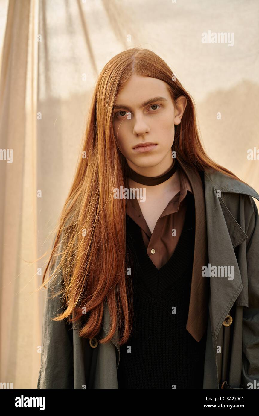 A young man with long hair showcases his style in a natural environment ...