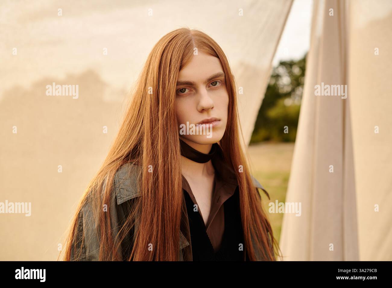 Long haired model presents stylish attire against a natural backdrop ...