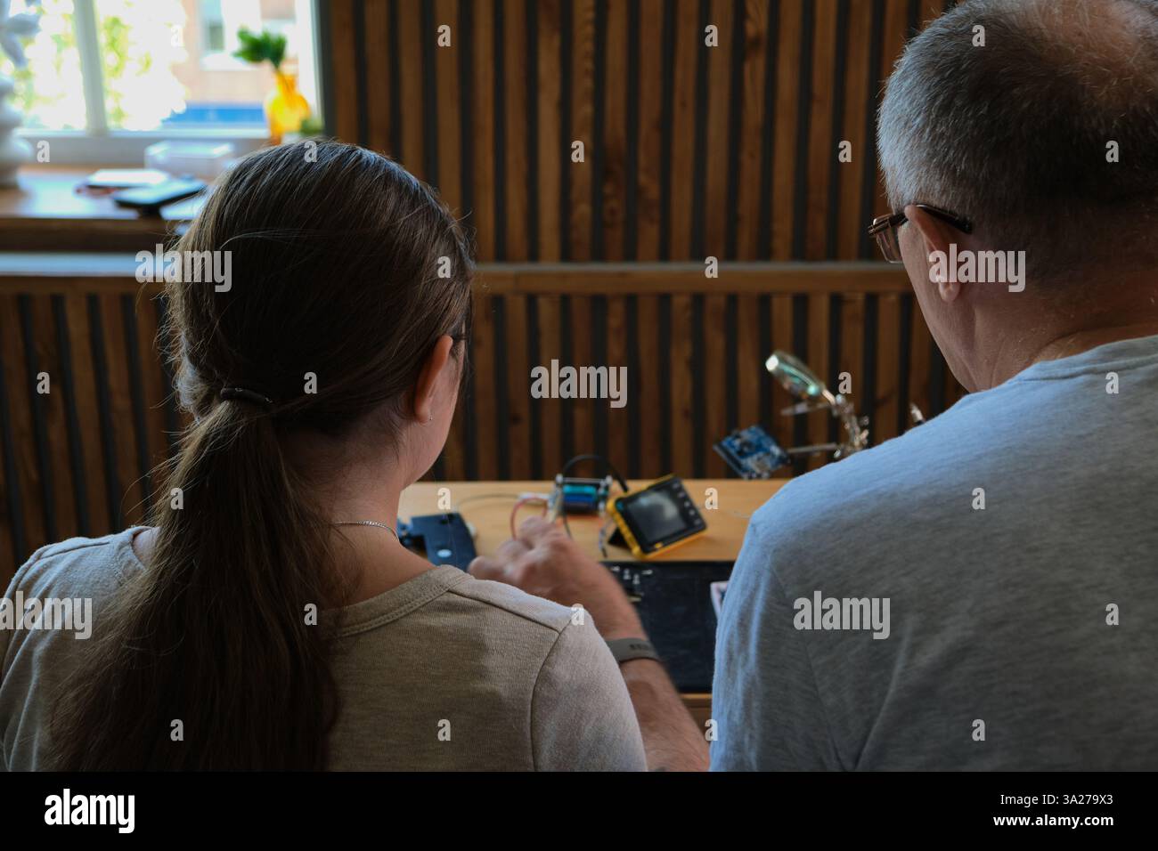 Grandfather teaches his granddaughter how to repair electronic devices ...
