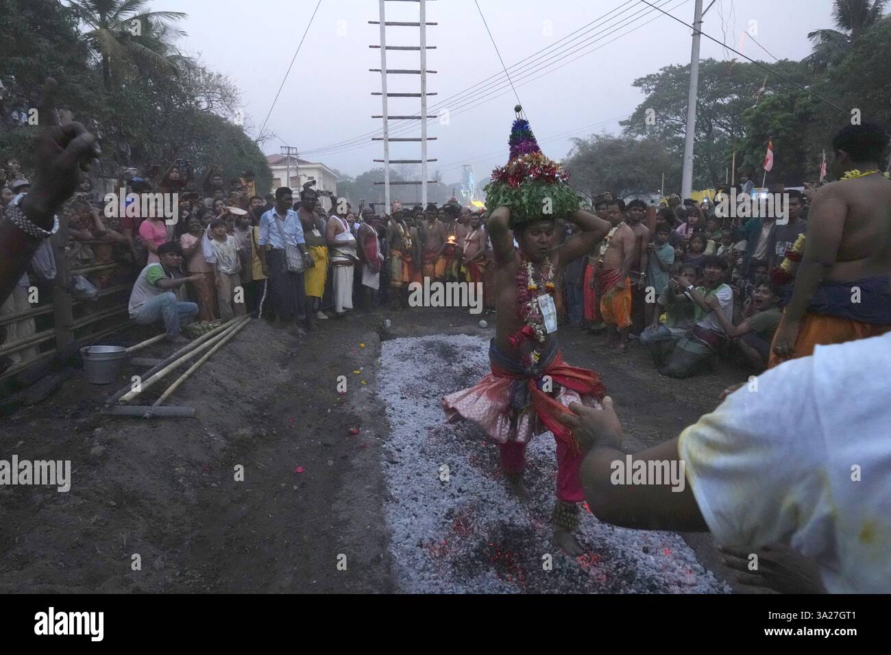 A Hindu devotee walks on burning embers in a pit during a traditional ...