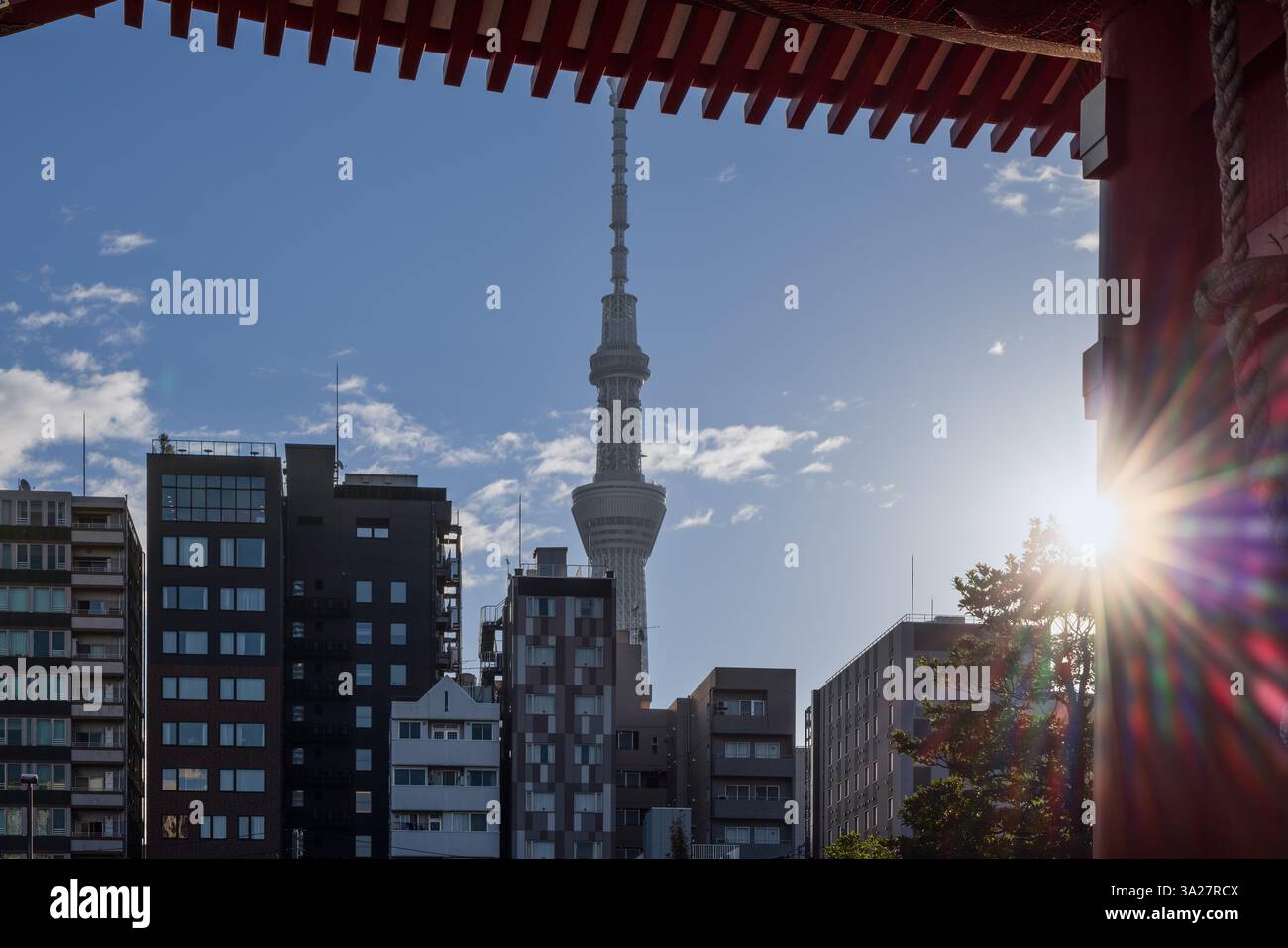 Tokyo Skytree rises above city buildings framed by the wooden architecture of a temple Senso-ji ...