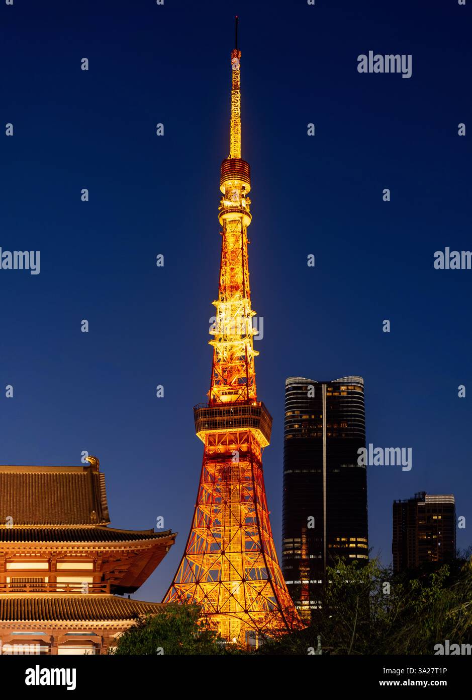 Glowing Tokyo Tower stands between the wooden eaves of Zojo-ji Temple ...