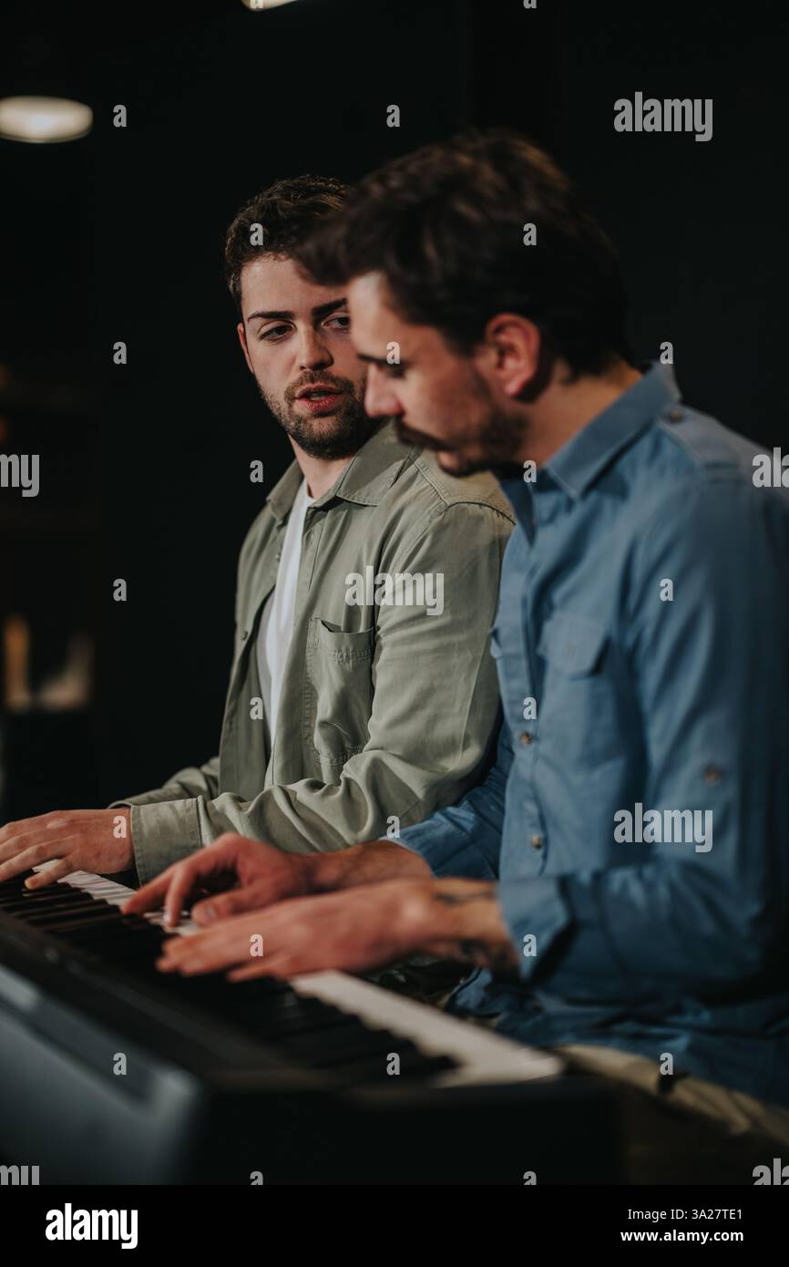 Two musicians collaborating and playing keyboard in a recording studio ...