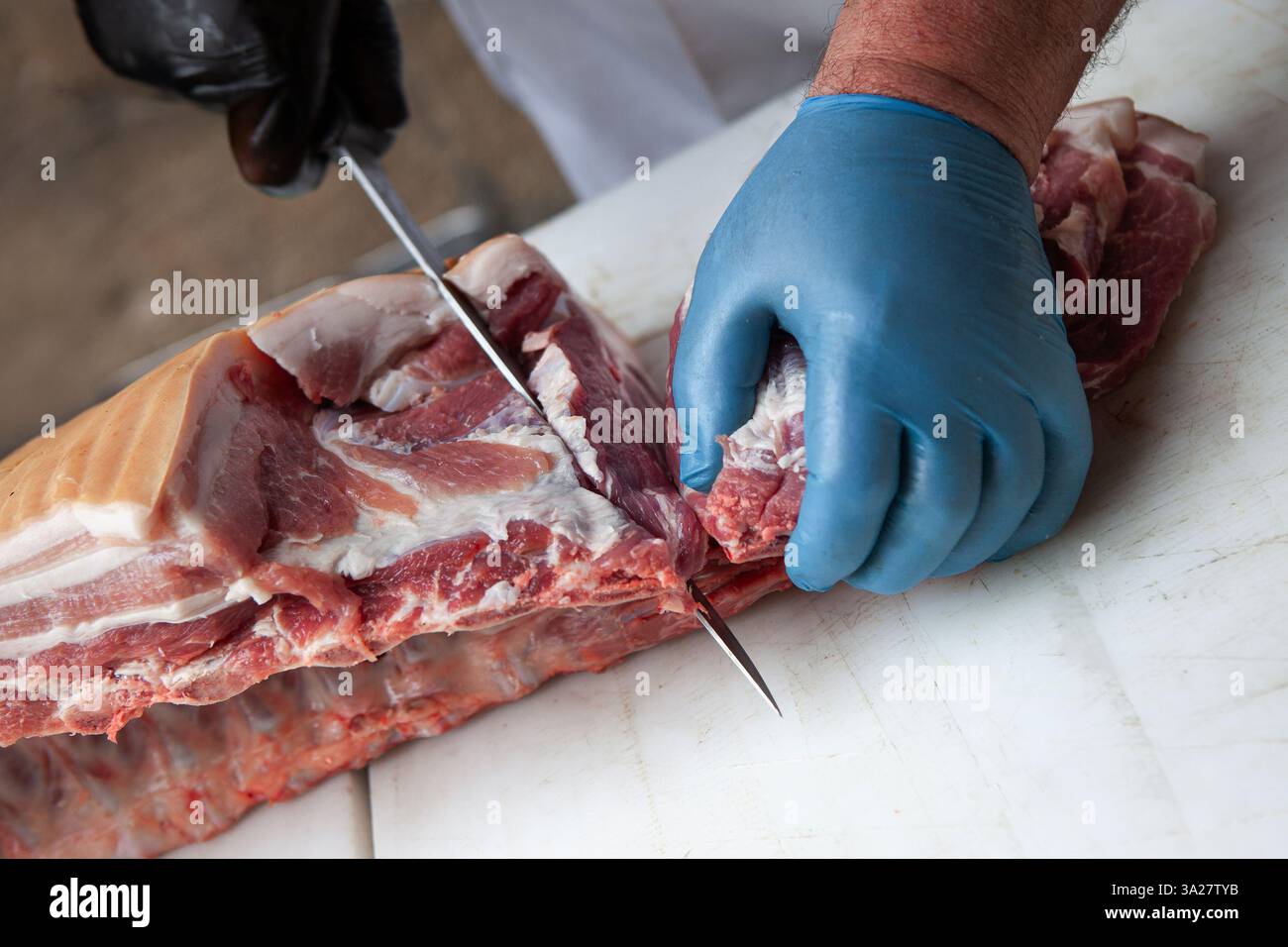Hand of the butcher cutting pork chops Stock Photo - Alamy