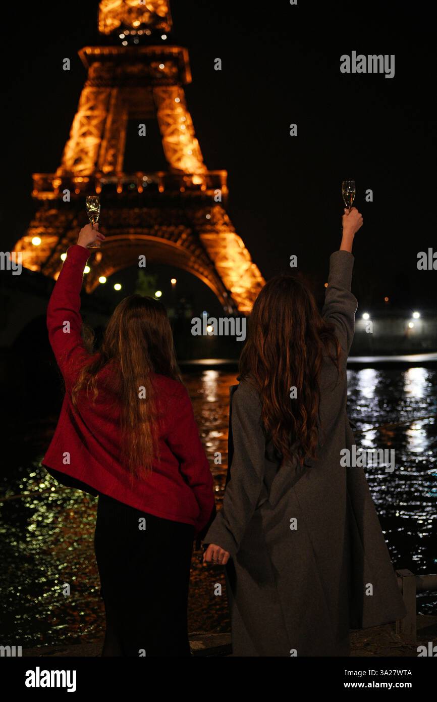 Two friends raise their glasses in front of the stunningly illuminated ...