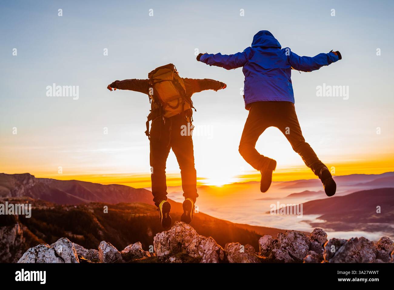 Two happy friends hikers during the hike joyful jumping on the mountain ...