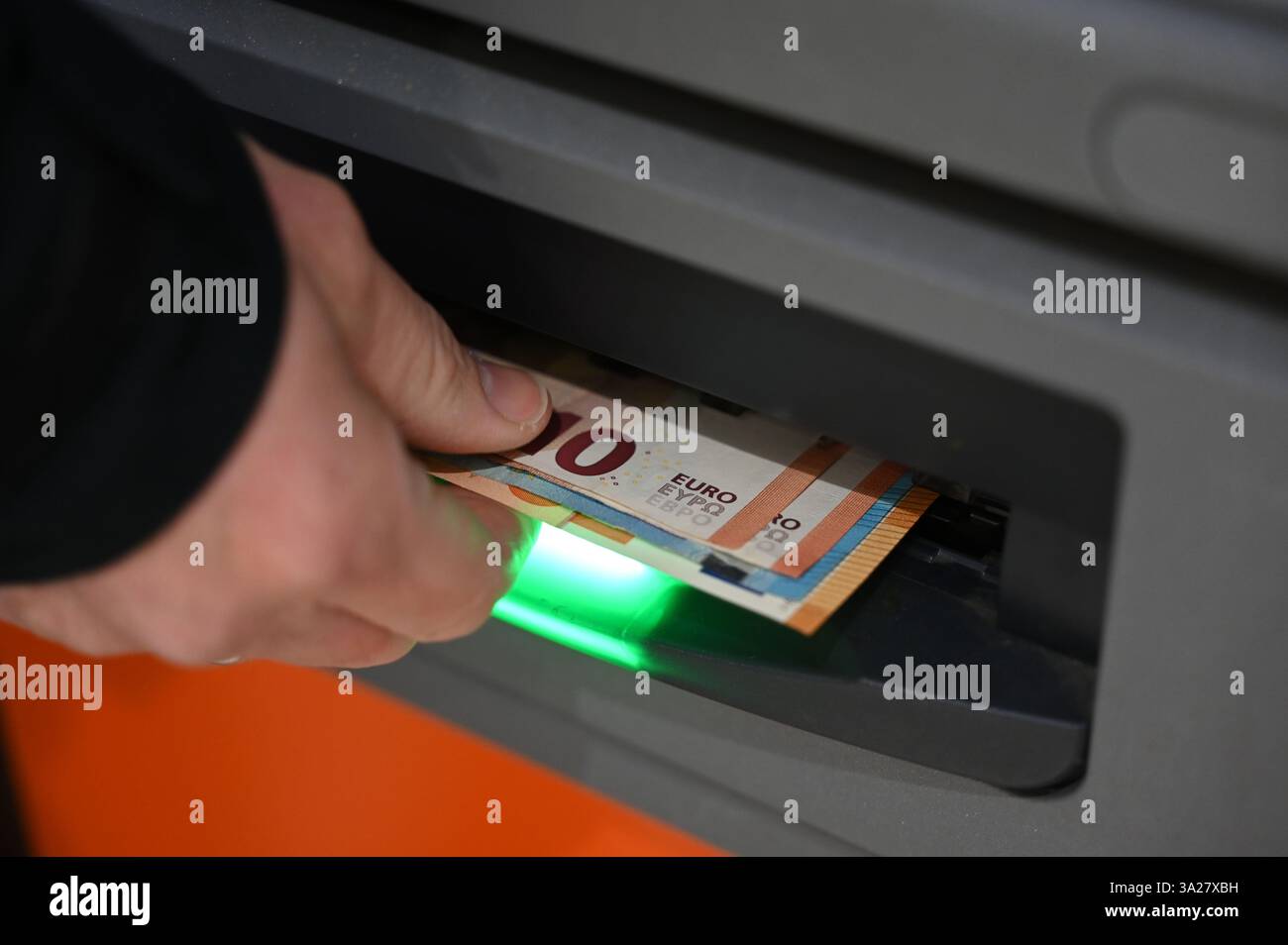 Leipzig, Germany. 12th Mar, 2025. A man pulls banknotes out of the ...