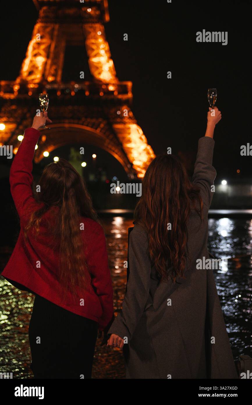 Two friends raise their glasses in celebration, beautifully lit by the ...