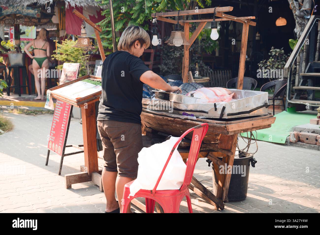 Vendor prepares fresh seafood at an outdoor market stall in Railay ...