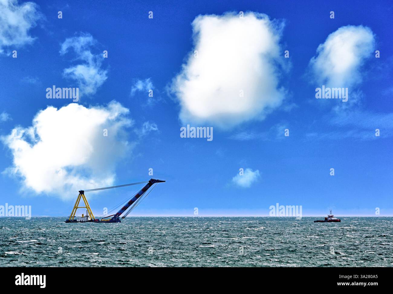 Floating barge crane being towed across the North sea by tug against ...