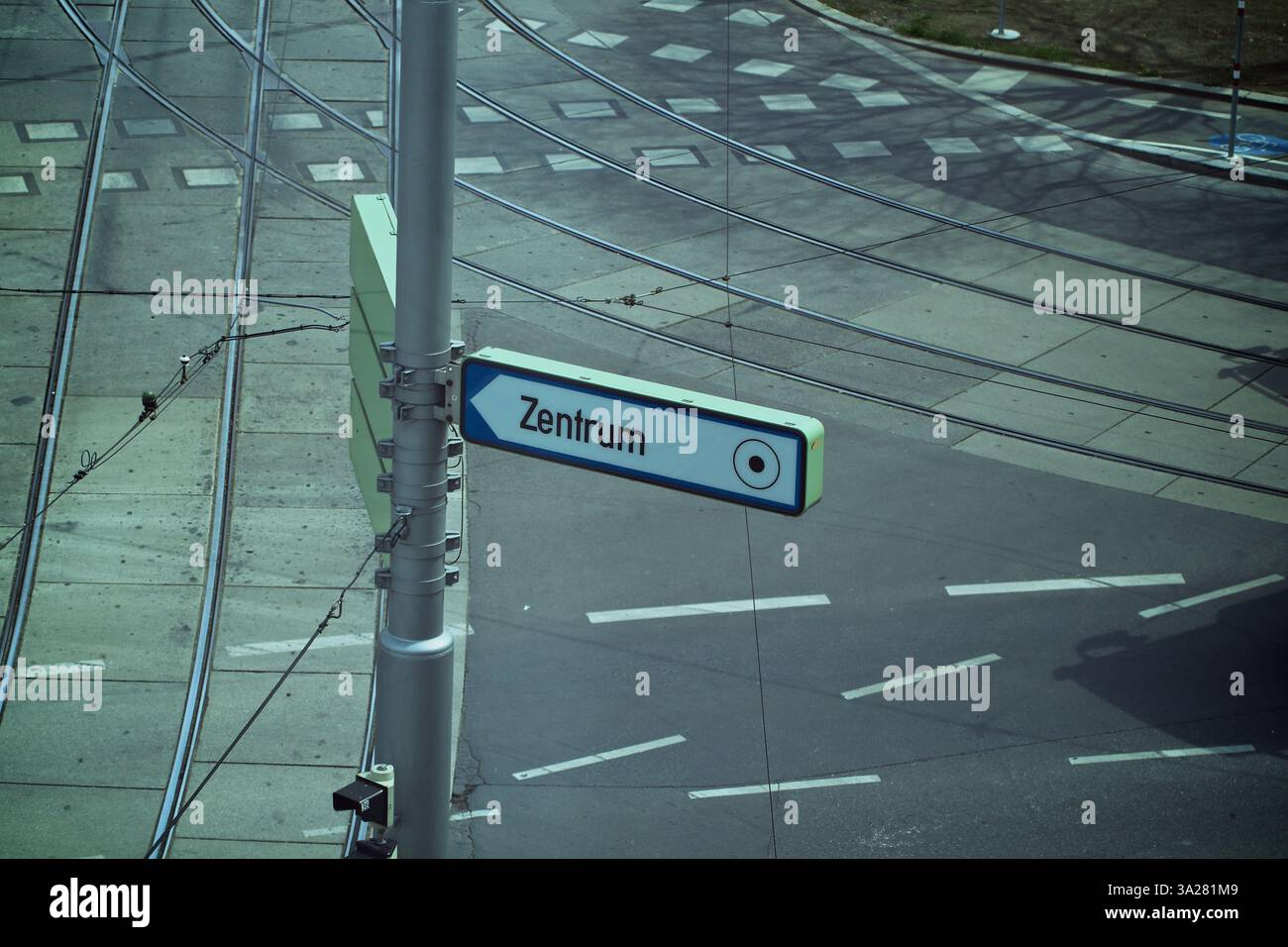 A street sign indicating 'Zentrum' on a pole, with tram tracks and road ...