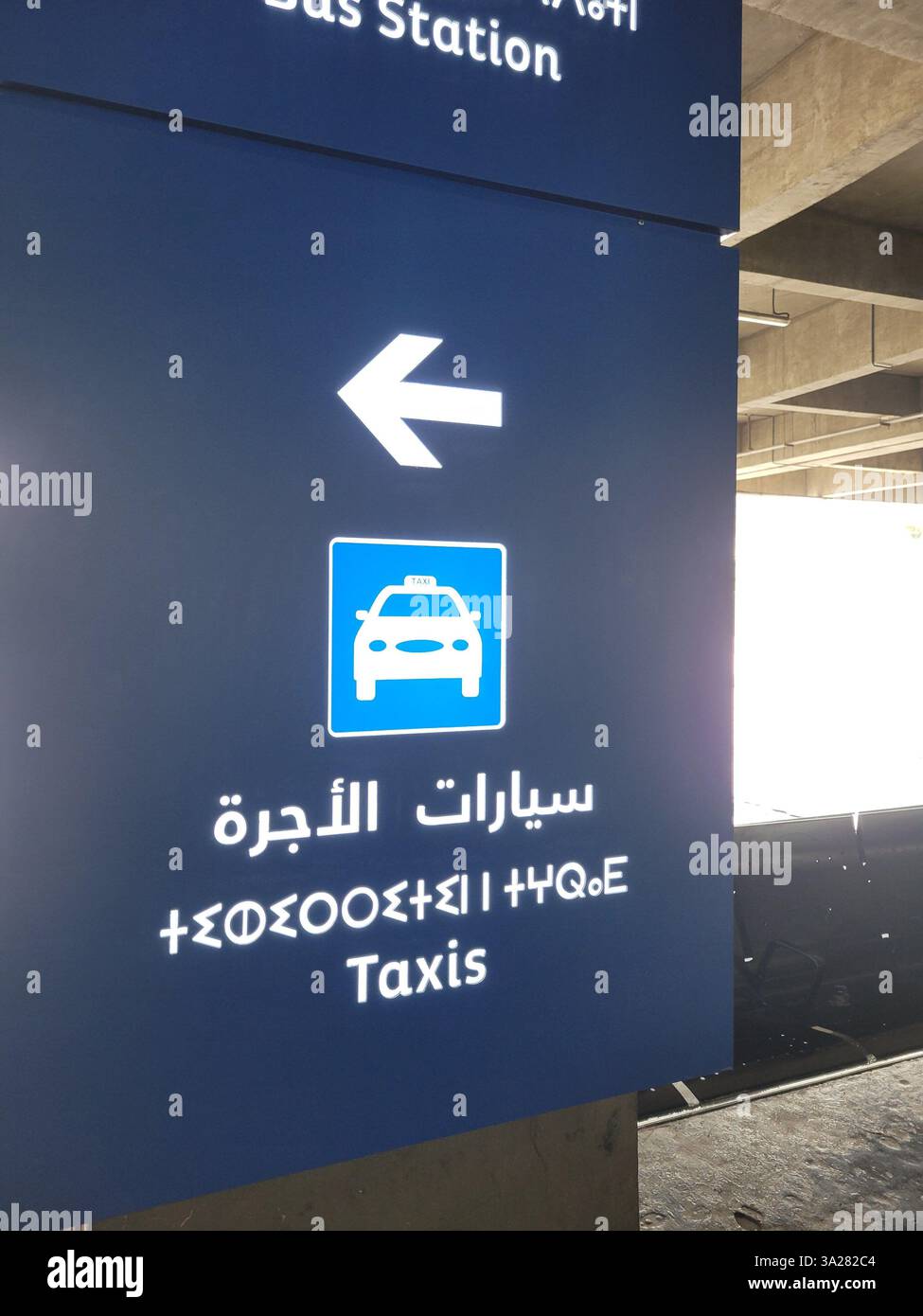 A bright blue sign is directing people to the taxis and bus station ...