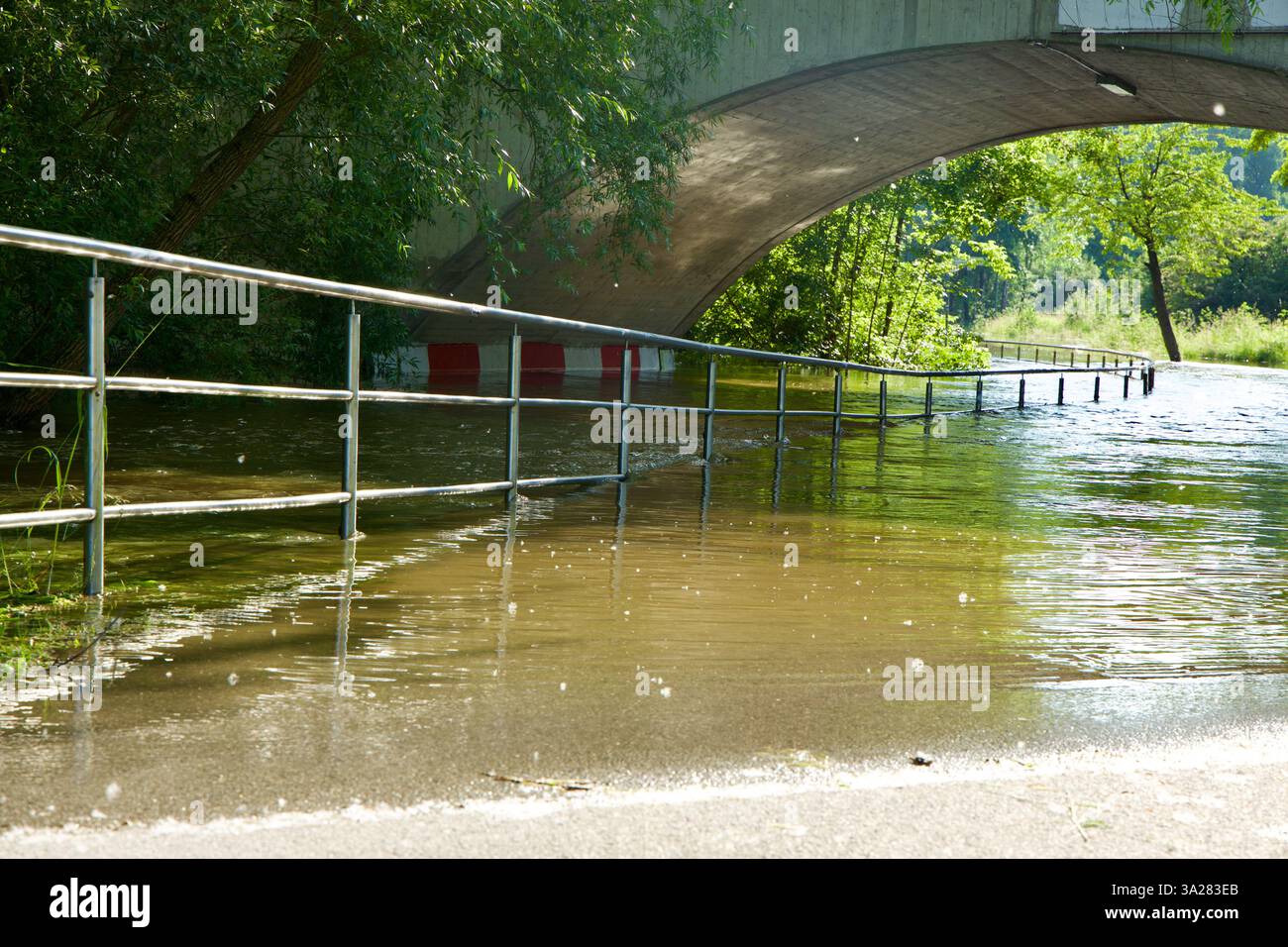 A pedestrian walkway beneath a bridge is submerged due to severe ...
