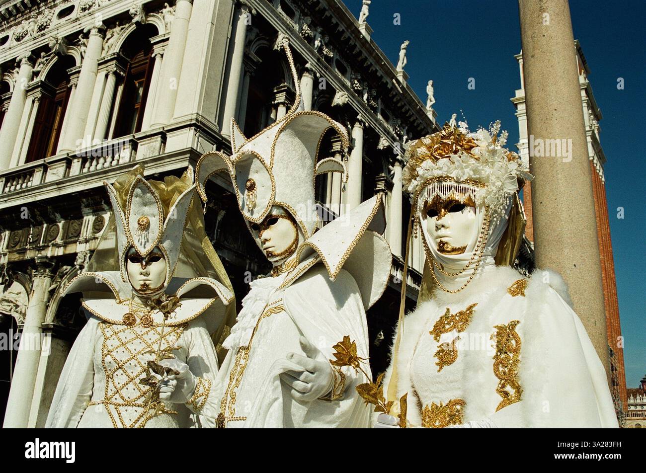 Three elegantly dressed figures in elaborate costumes and masks ...