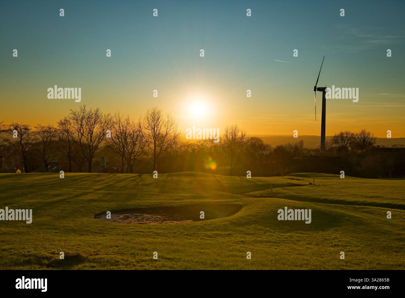 Sunset over a golf course with a single wind turbine, Bury, Greater ...