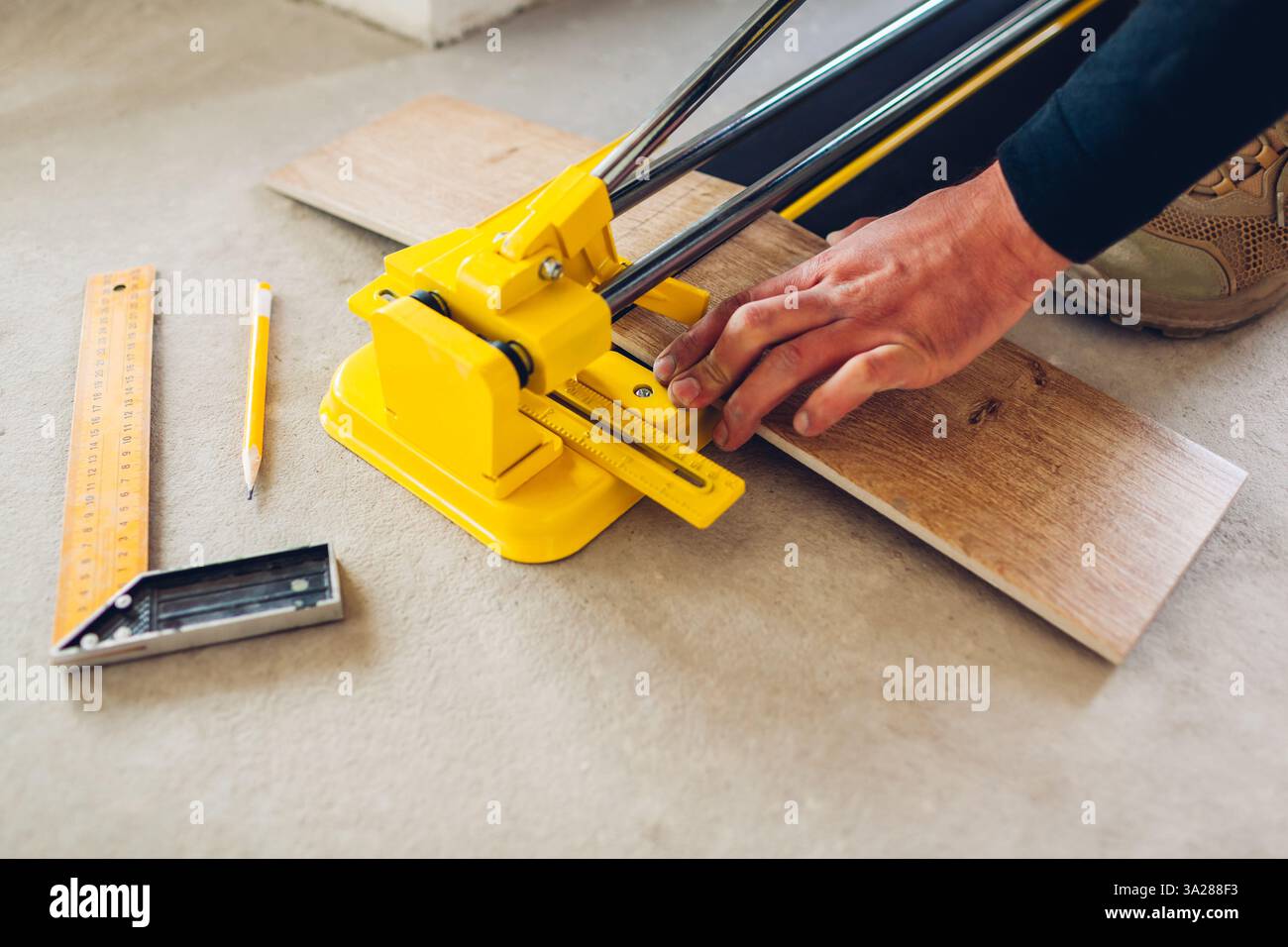 Construction worker using manual tile cutter equipment for laying ...