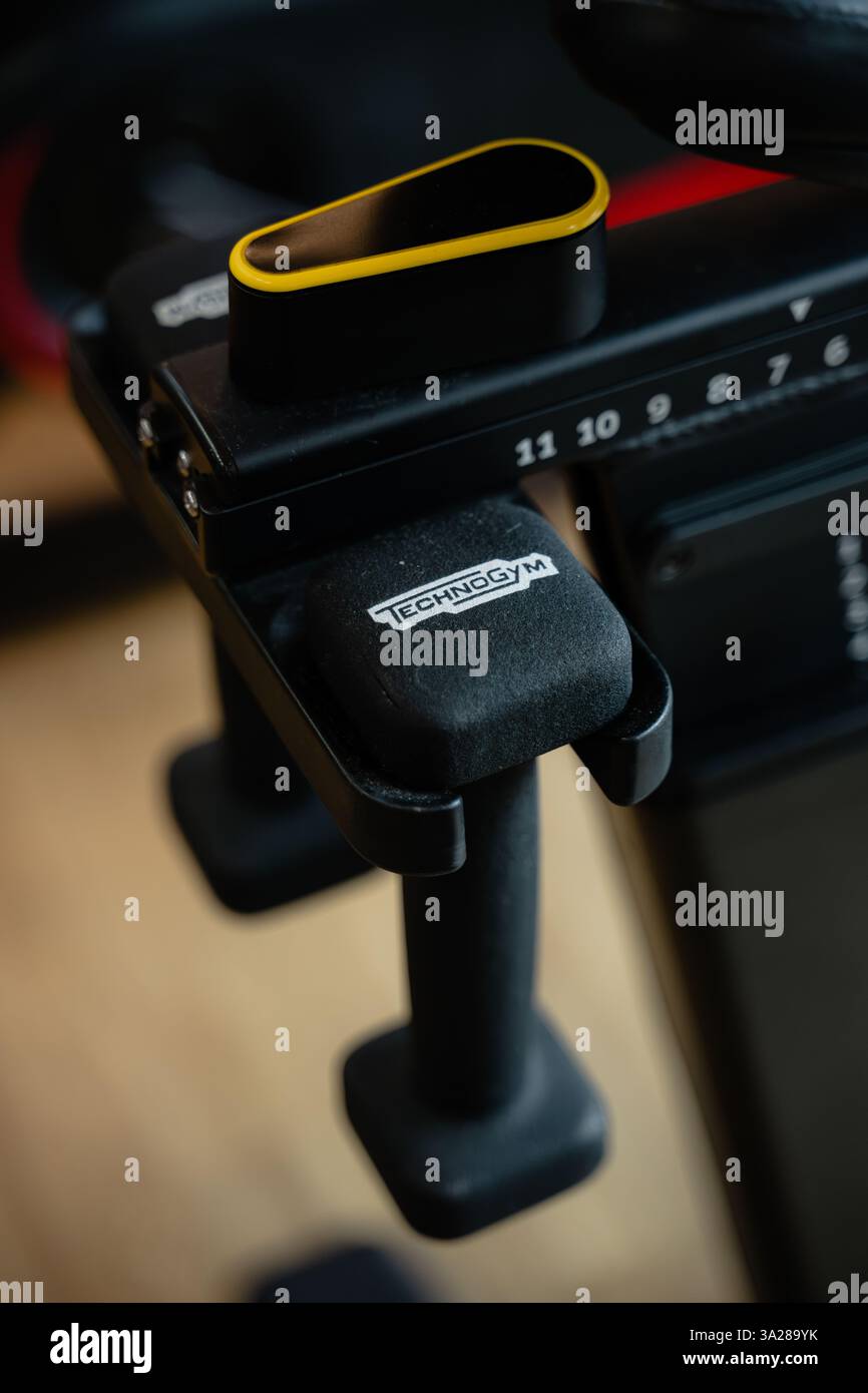 A Technogym weight lifting device is displayed in black and yellow. The ...