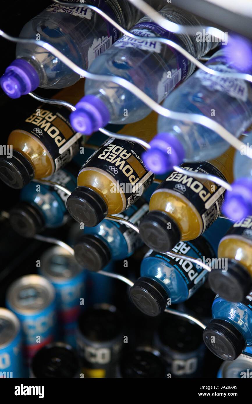A row of Powerade bottles are on a shelf. The bottles are in various ...