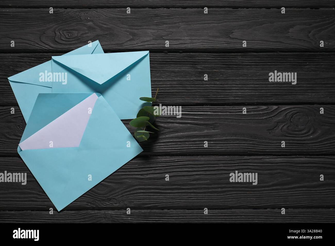 Paper envelopes with letter and eucalyptus branch on black wooden ...