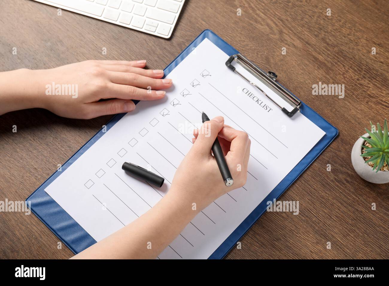 Woman filling Checklist at wooden table, above view Stock Photo - Alamy