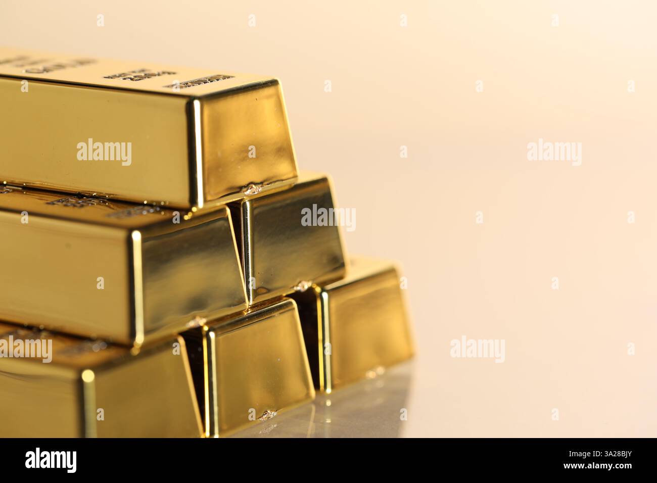 Many stacked gold bars on beige background, closeup. Space for text ...