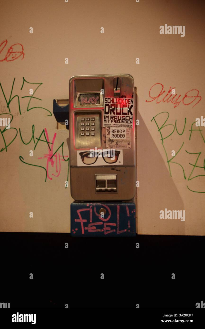 A vintage payphone mounted on a wall, surrounded by colorful graffiti ...