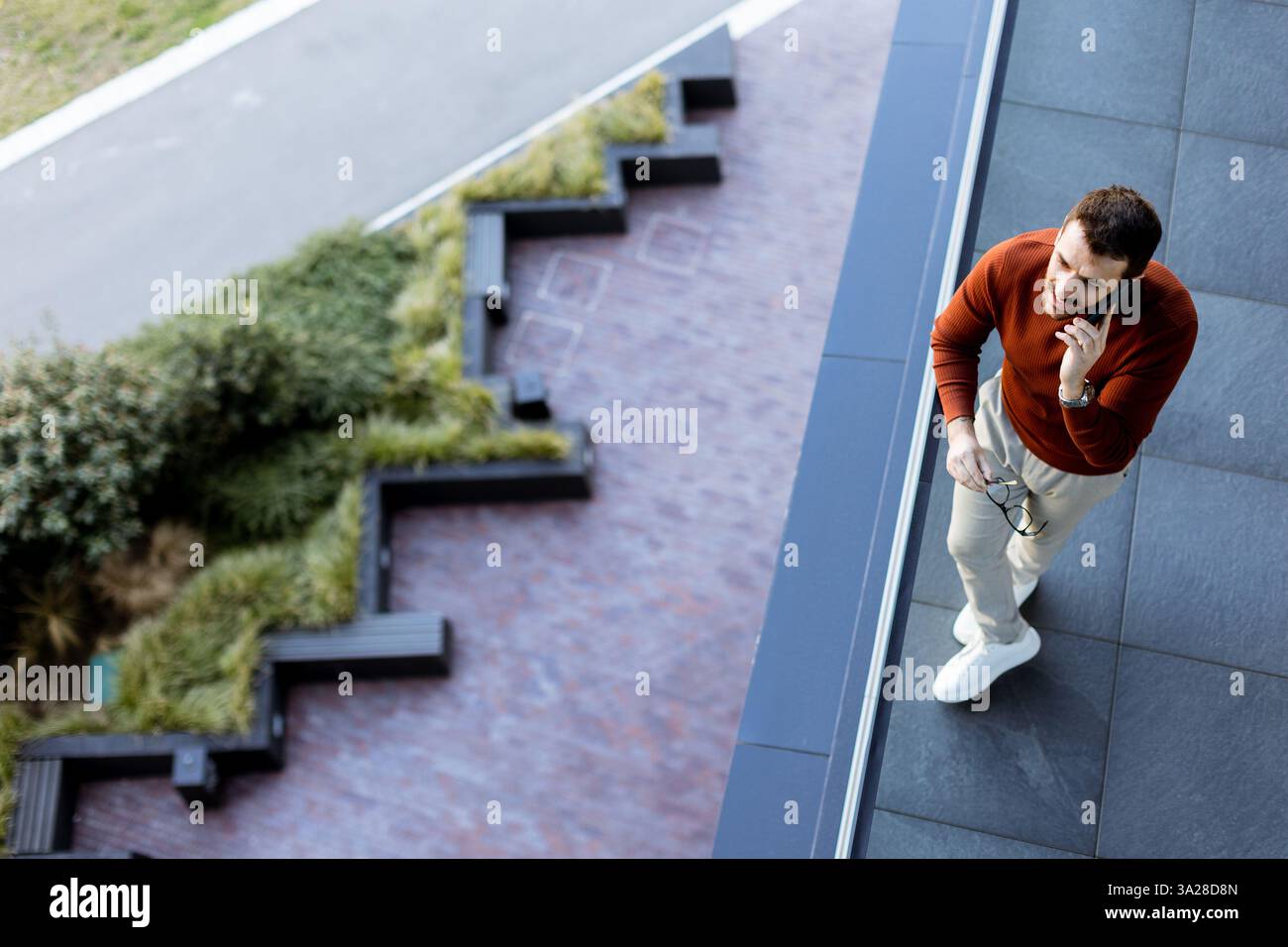 A young man stands on a sleek balcony while engaged in an animated ...