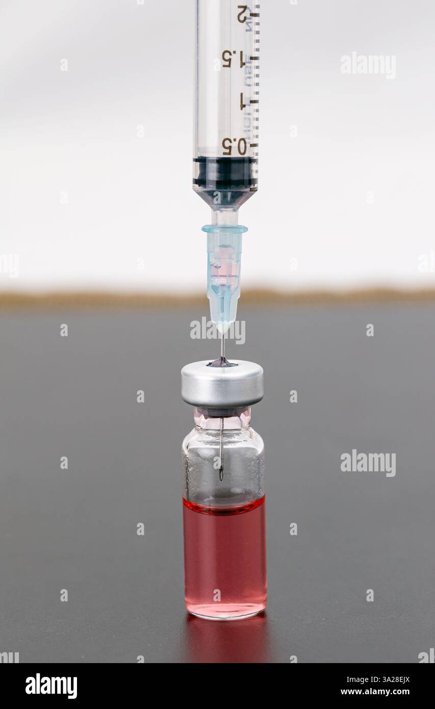 Syringe with red liquid on a black and white background representing ...