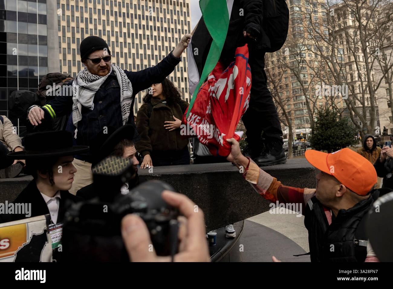 New York, United States. 12th Mar, 2025. A man rips a flag away from a ...