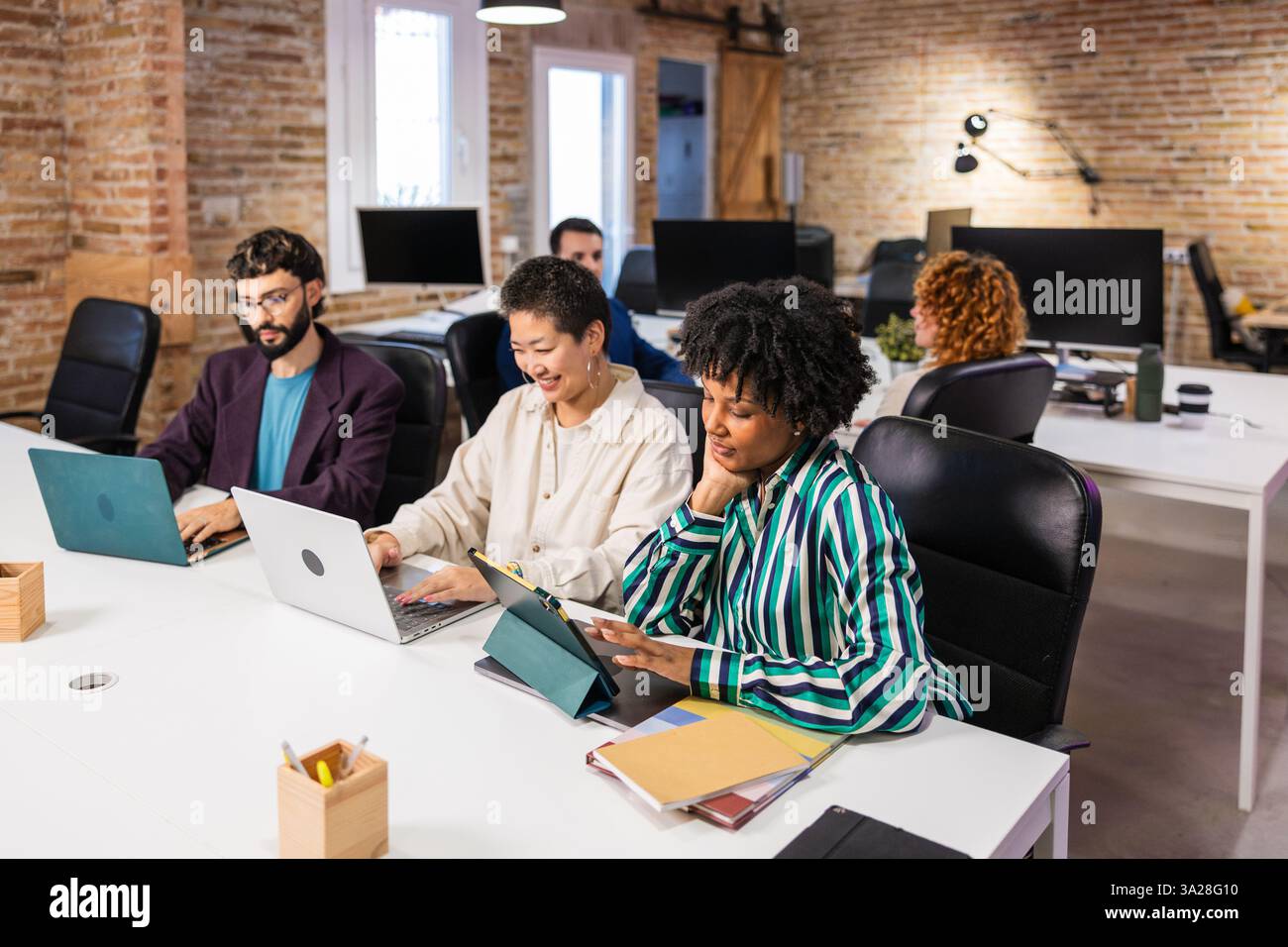 Multi ethnic team collaborating on project in modern office Stock Photo - Alamy