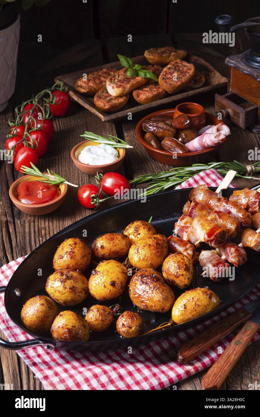 Rustic dates wrapped in bacon and young roasted potato Stock Photo - Alamy