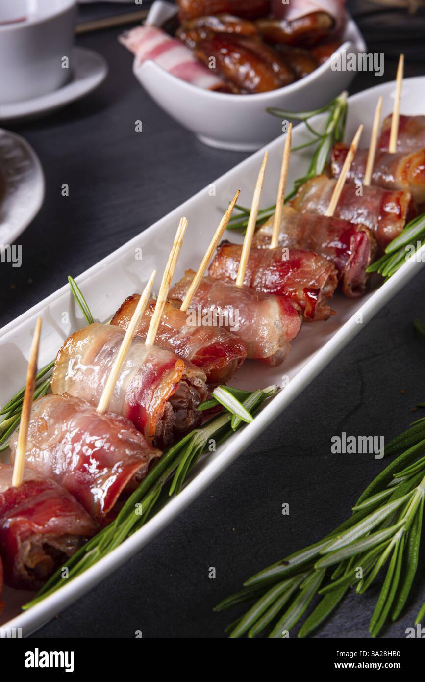 Dates wrapped in bacon and delicious tapas Stock Photo - Alamy