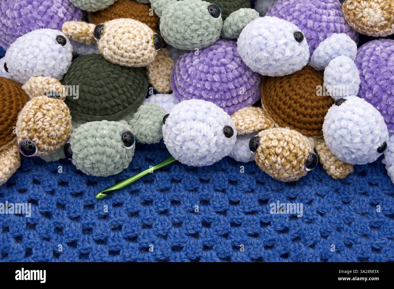 Close up on hand crochet yarn turtles in greens, browns and purples on ...