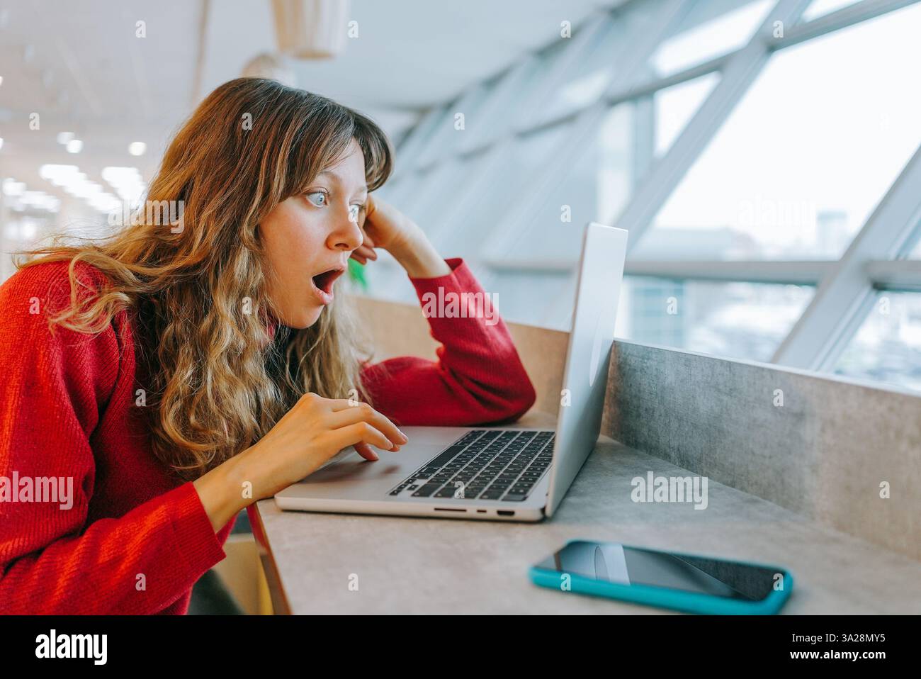 Shocked woman with wide opened eyes and mouth reading unbelievable news ...