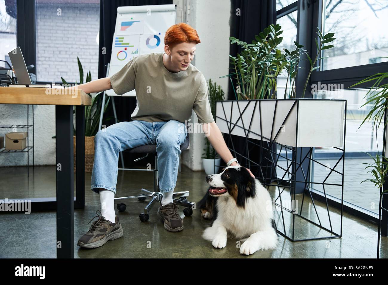 A young man with red hair enjoys his work in a modern office while ...
